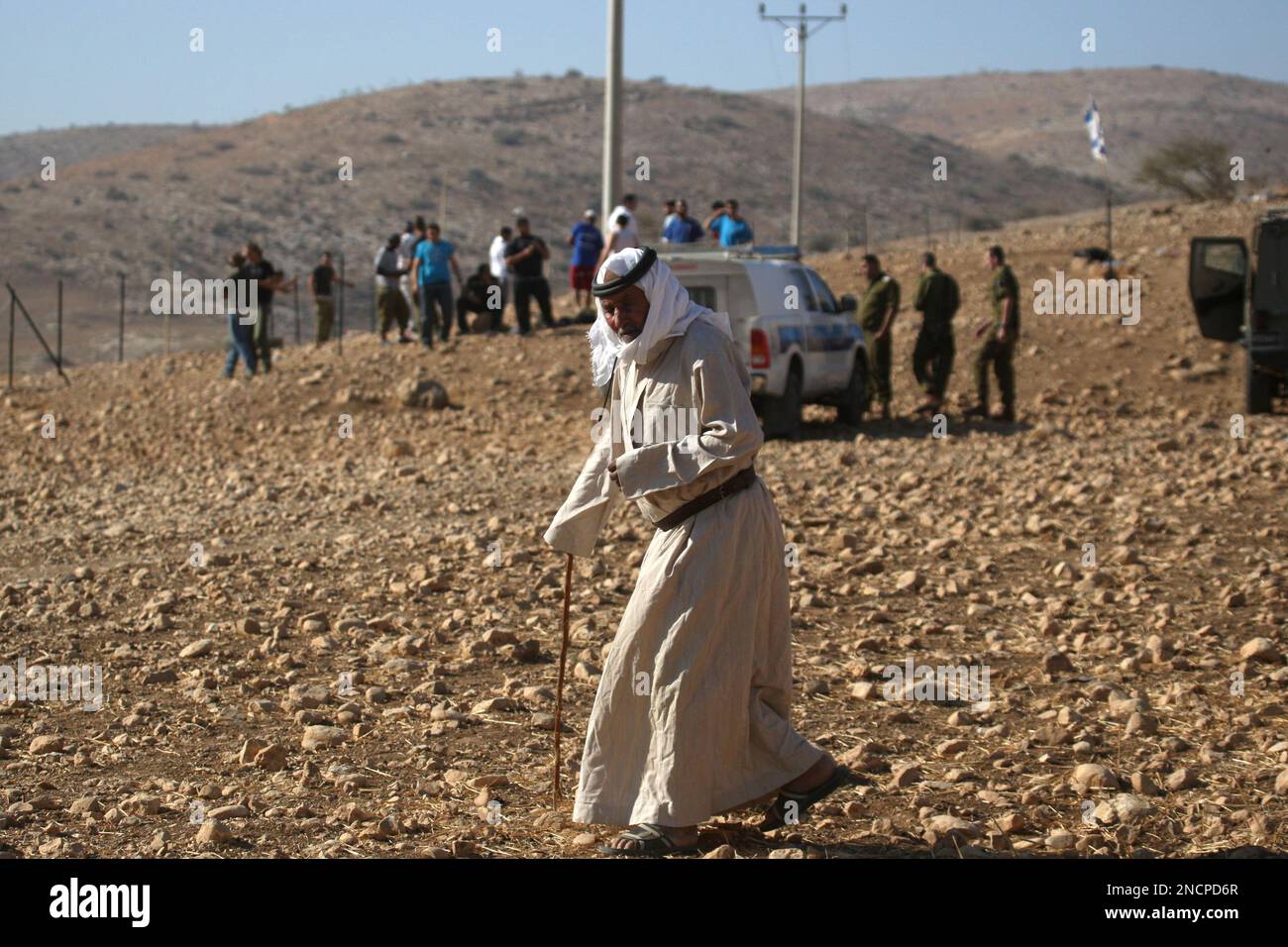 With Israeli soldiers and Jewish settlers in the background, a Bedouin ...