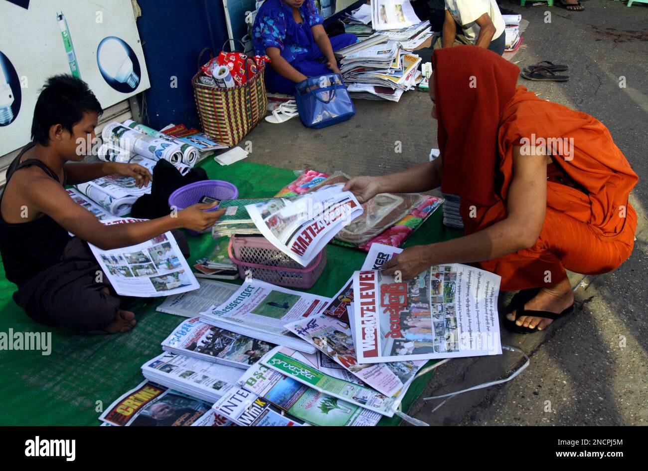 A Myanmar Buddhist monk, right, buys a copy of a weekly journal from a ...