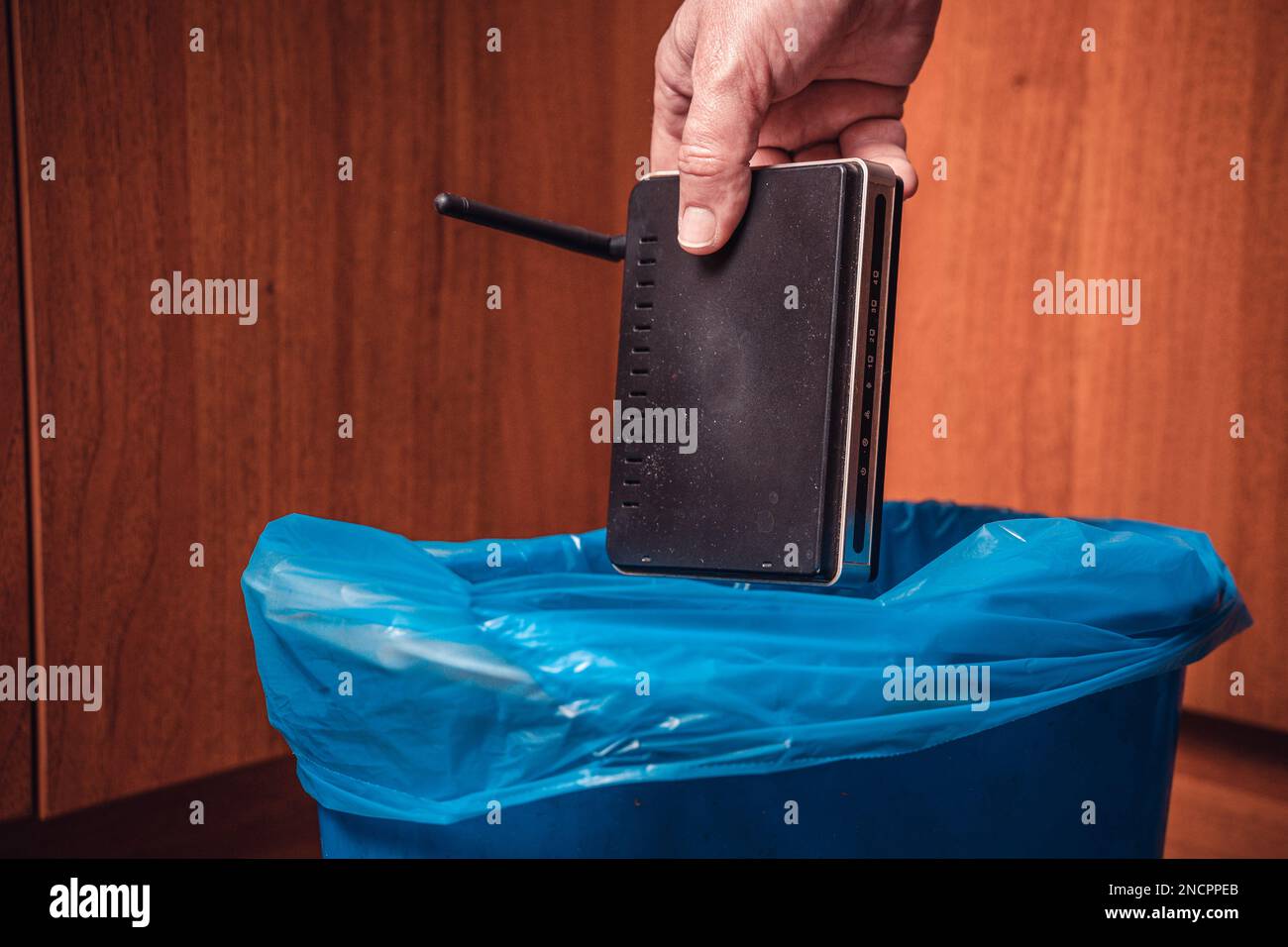 A man throws a WiFi router in the trash. Man's hand with a WiFi router ...