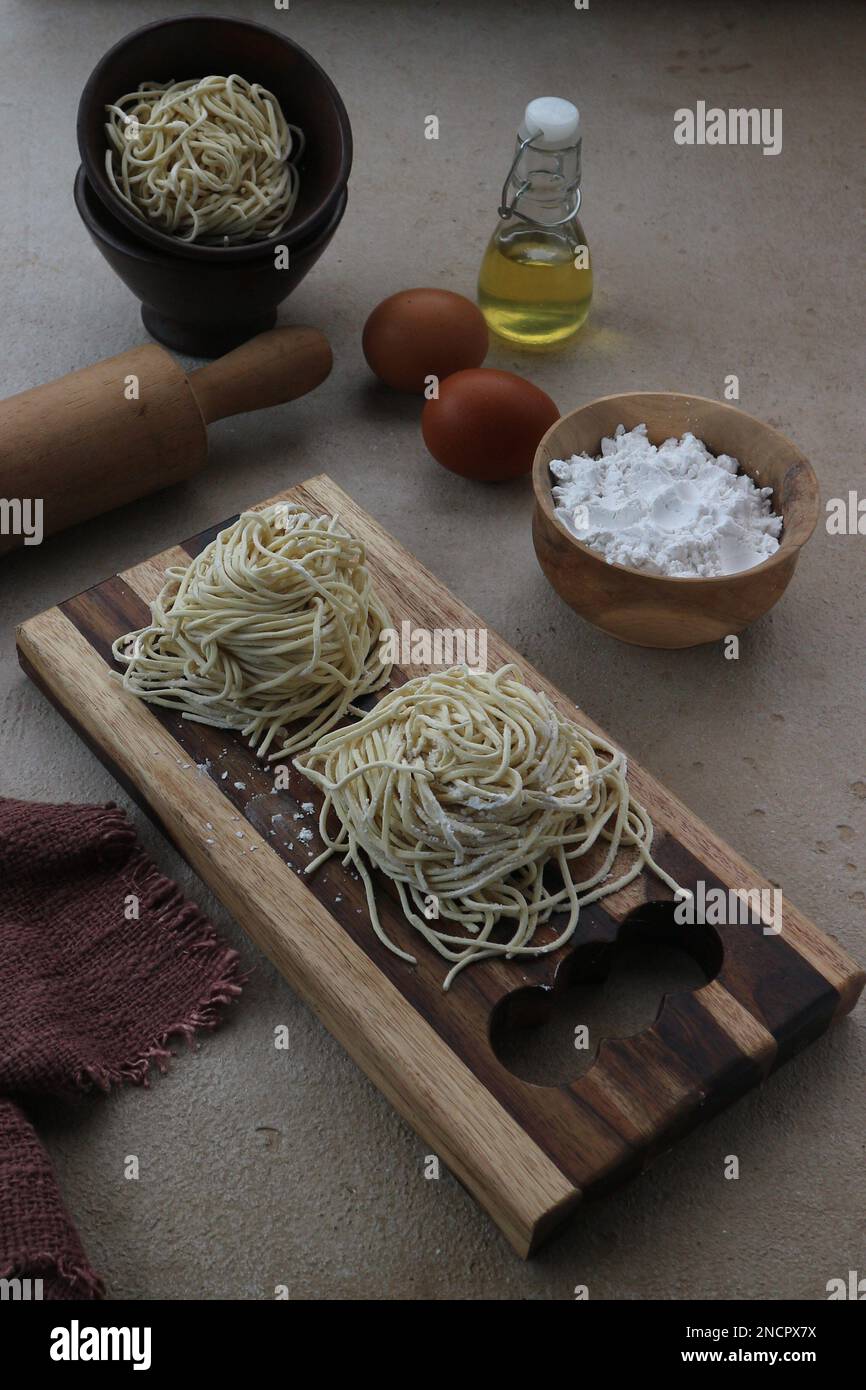 fresh noodles on a wooden tray with the ingredients of a bowl of flour ...