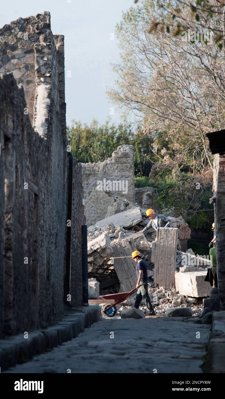 Workers stand among debris in the ancient Roman city of Pompeii, Italy ...