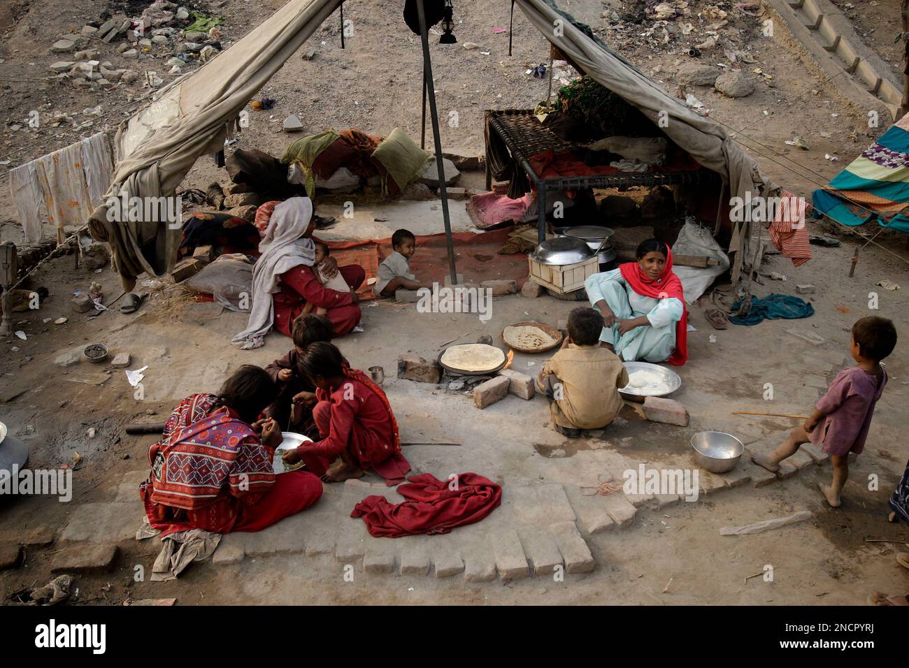 A Pakistani woman prepares food for her children outside their tent at ...