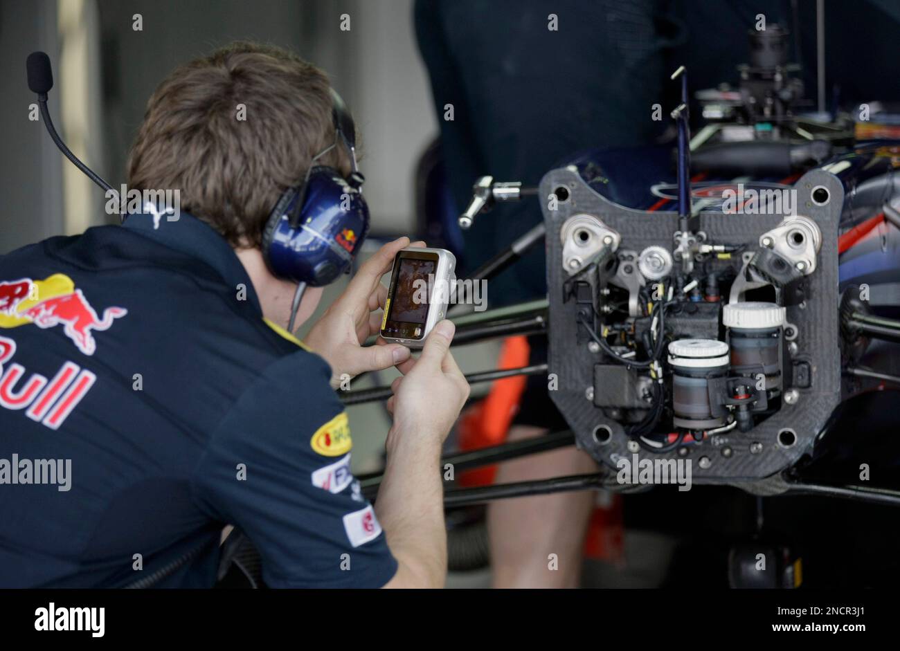 A Red Bull mechanic takes a photograph of Mark Webber's car before a ...