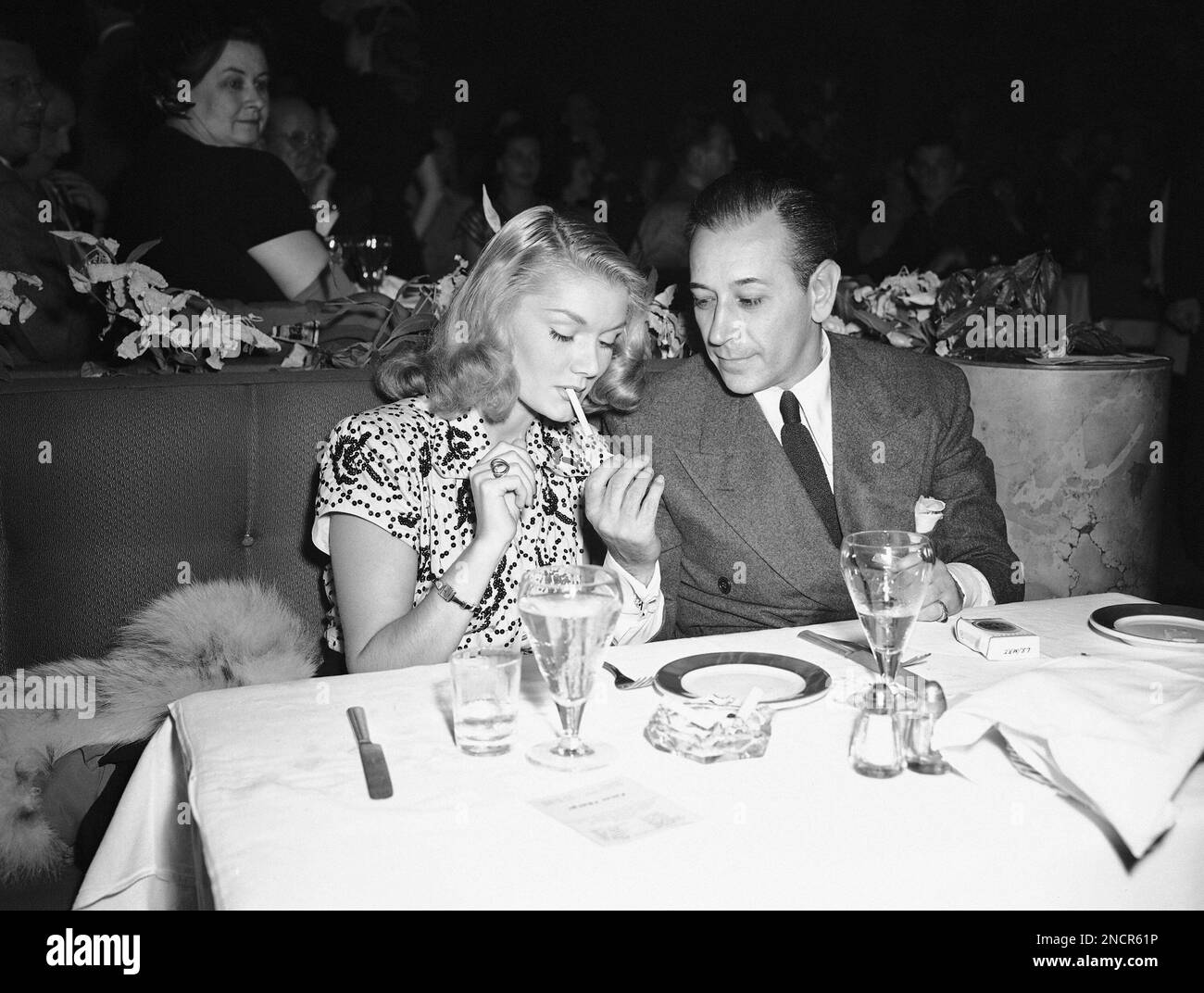 Screen star George Raft lights a cigarette for his date, actress Eve ...