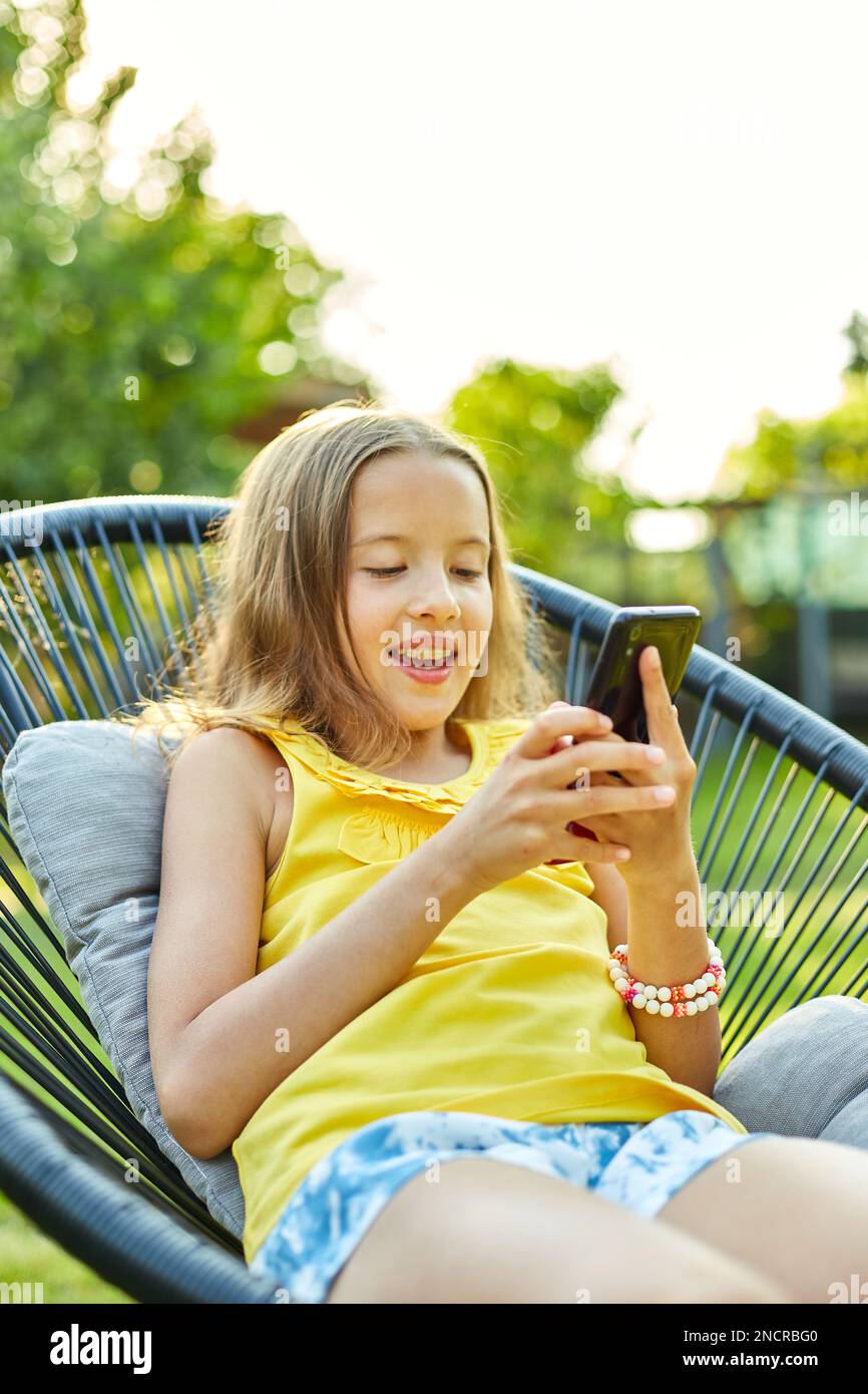 Happy kid girl playing game on mobile phone in the park outdoor, child ...