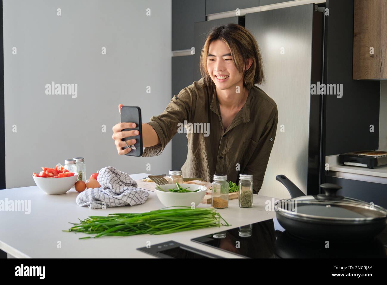 Asian young man taking a selfie while cooking at kitchen Stock Photo ...