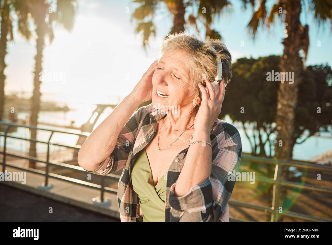 Happy, music and singing with old woman at beach for streaming, freedom ...