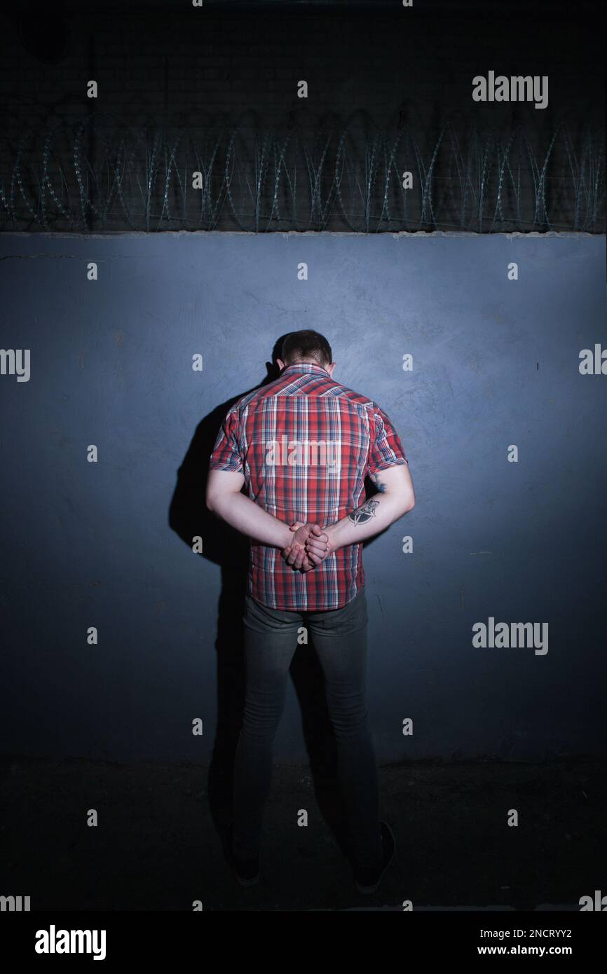 Arrested criminal male on barbed wire background Stock Photo - Alamy