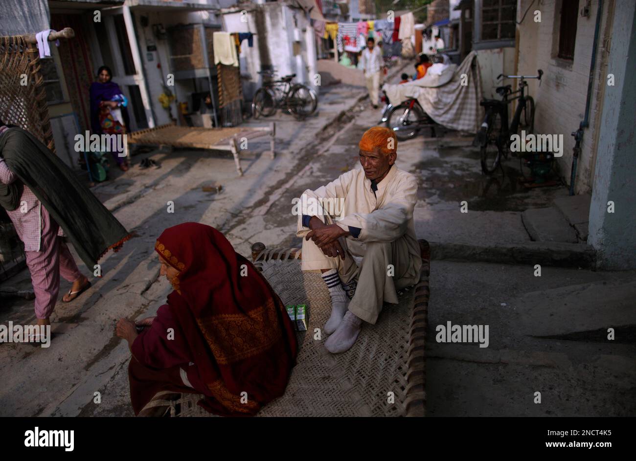 An elderly Pakistani couple sits in front of their house in an alley of ...