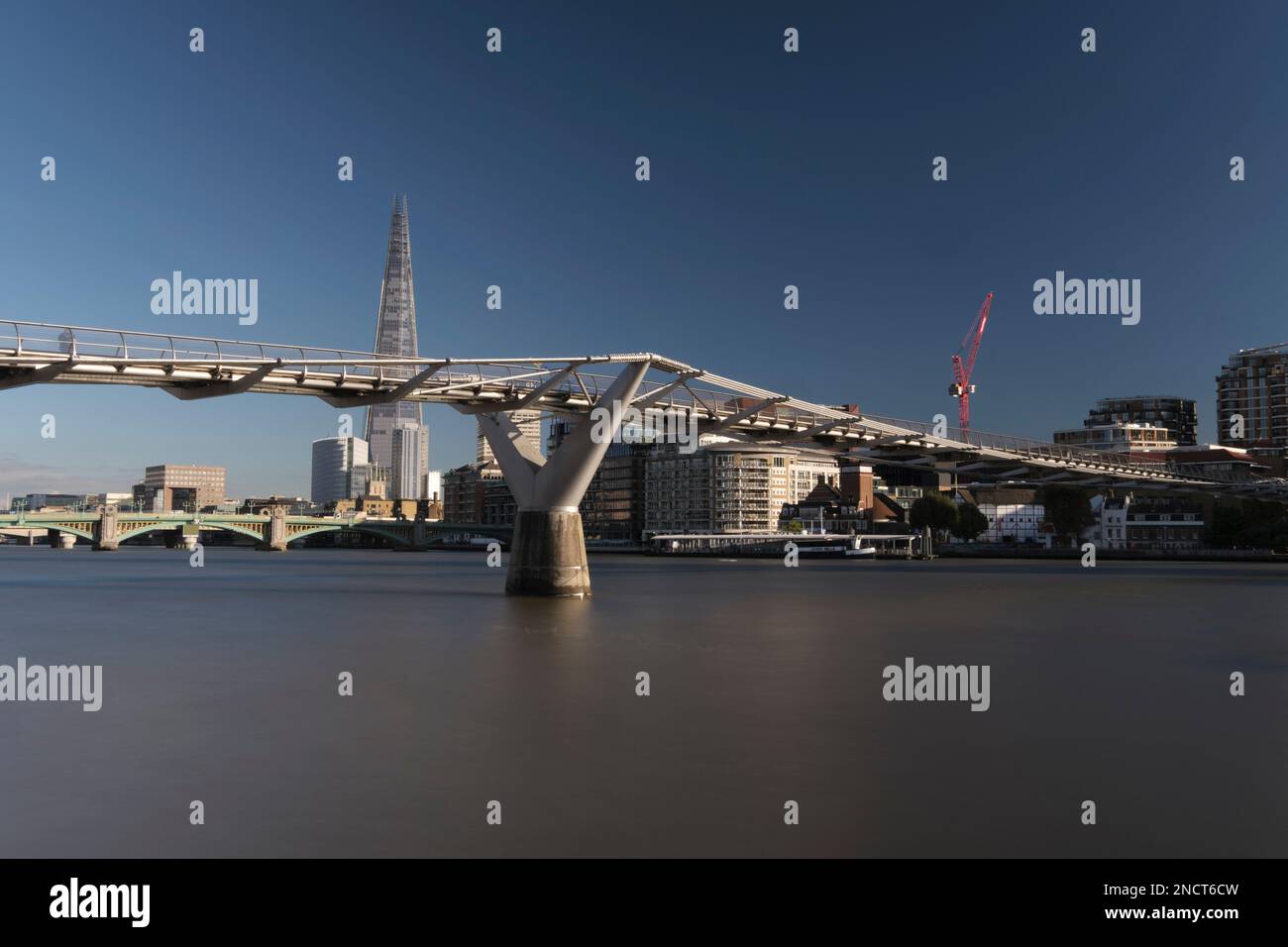 Wide shot of pedestrian bridge across Thames in London with Modern ...