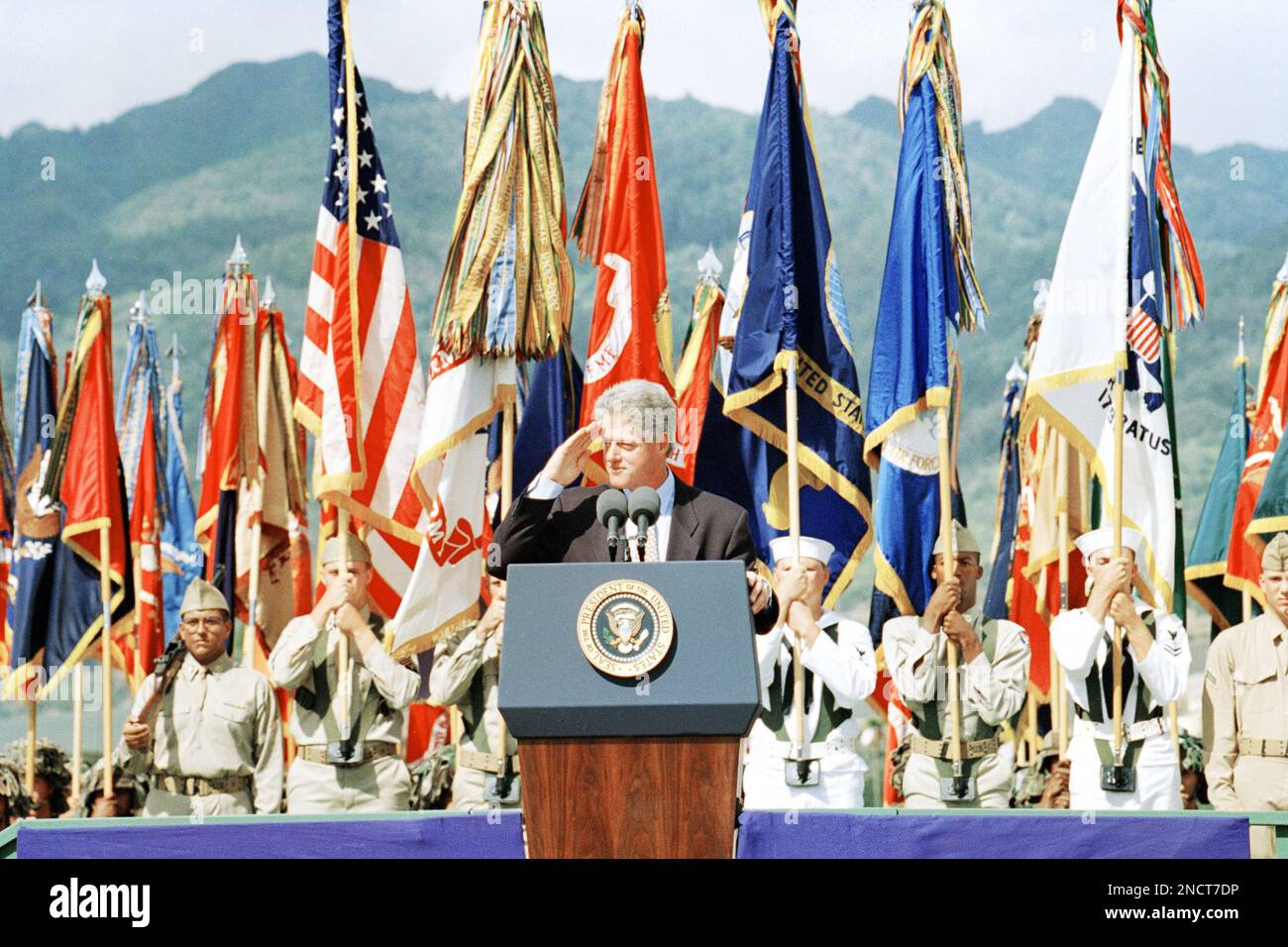 President Bill Clinton salutes troops as he stands at a podium at ...