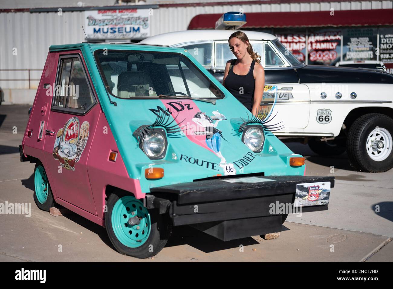 A young female next to an old micro car parked in front of the ...