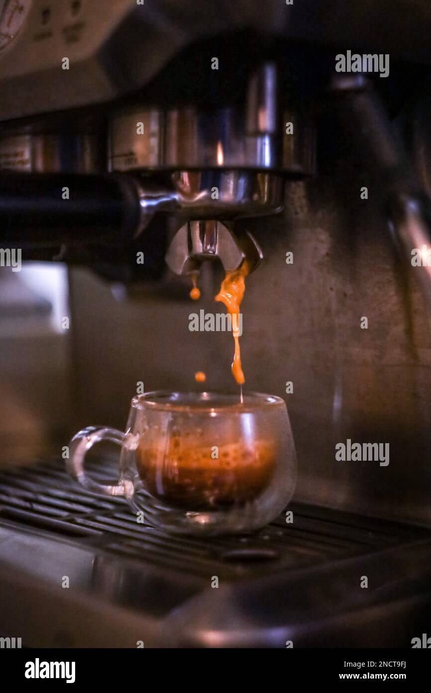 A vertical close-up of a manual coffee machine brewing into a ...