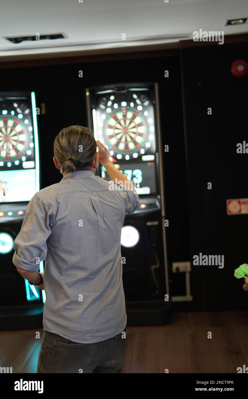A vertical shot of a man playing darts at an amusement arcade Stock ...