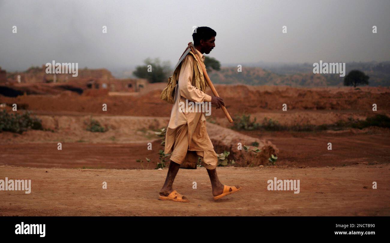 A Pakistani man walka back home after finishing his daily work at a ...