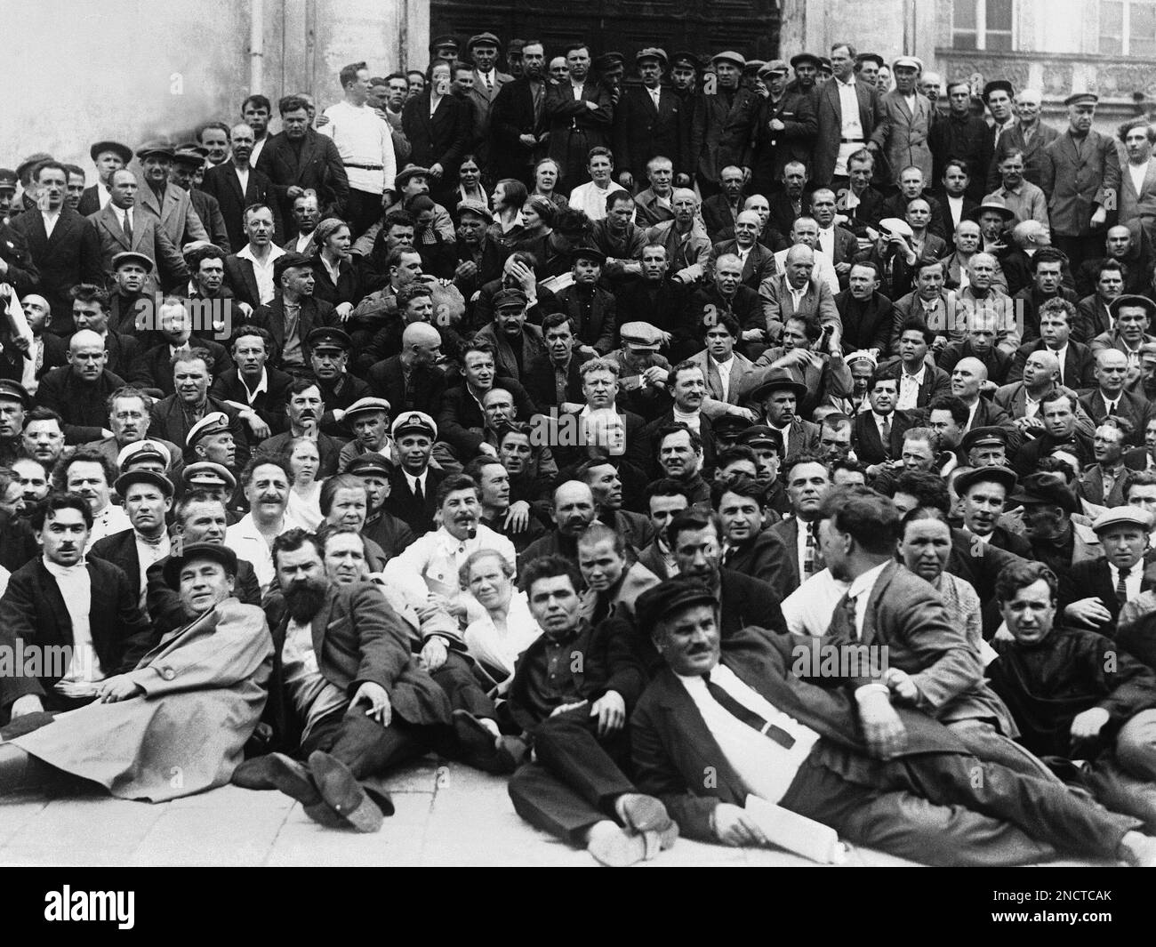 Joseph Stalin, in centre near front, dressed in a shirt and smoking a ...
