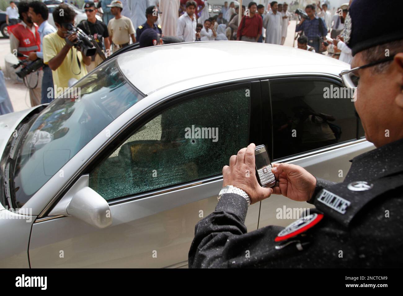 A Pakistani police officer takes picture of the car targeted by unknown ...