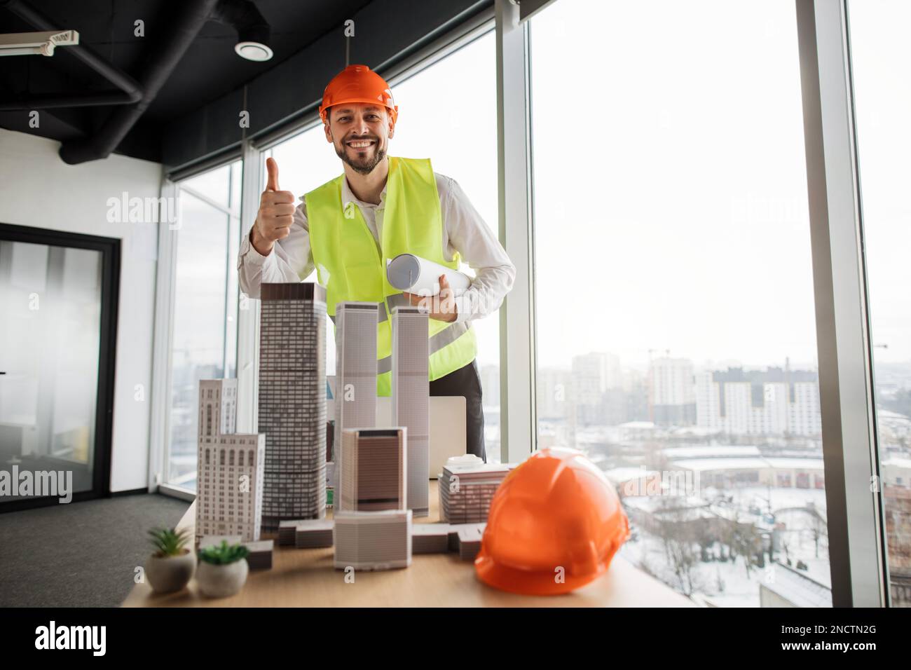 Architect man or male builder adding component to a building model ...