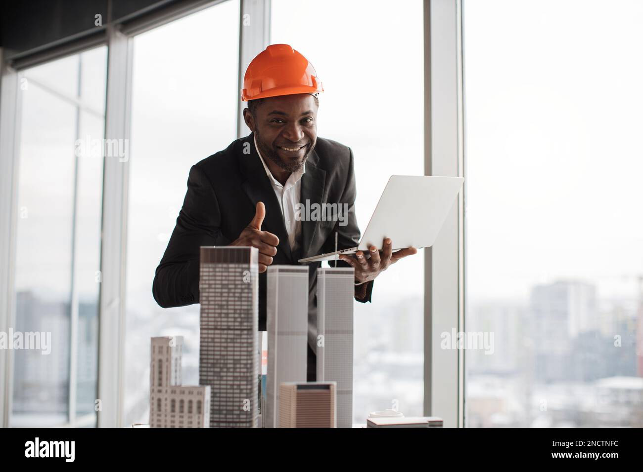 Happy african man in orange construction hard hat and suit showing ...