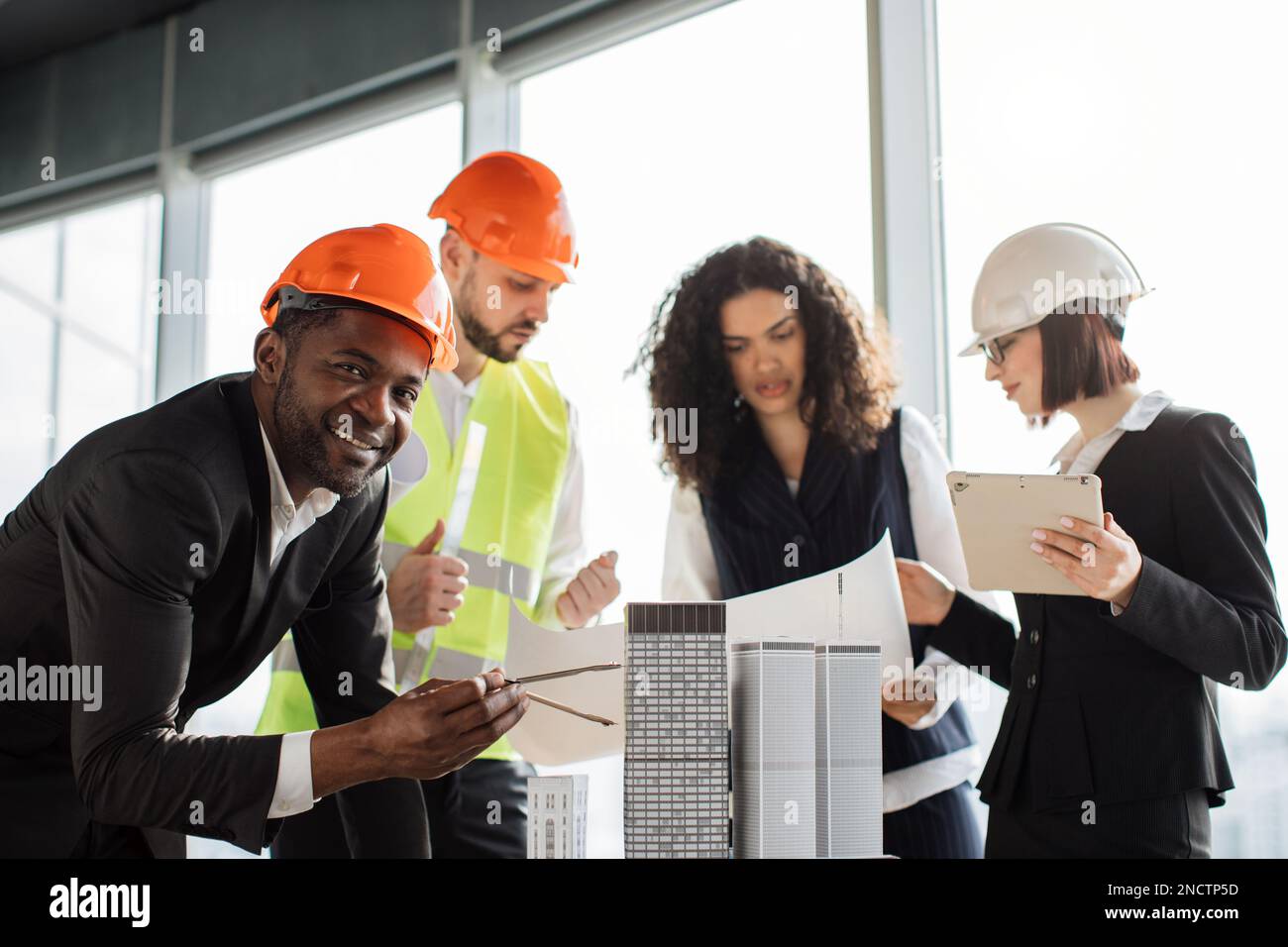 African engineer in protective helmet measuring city model using ...