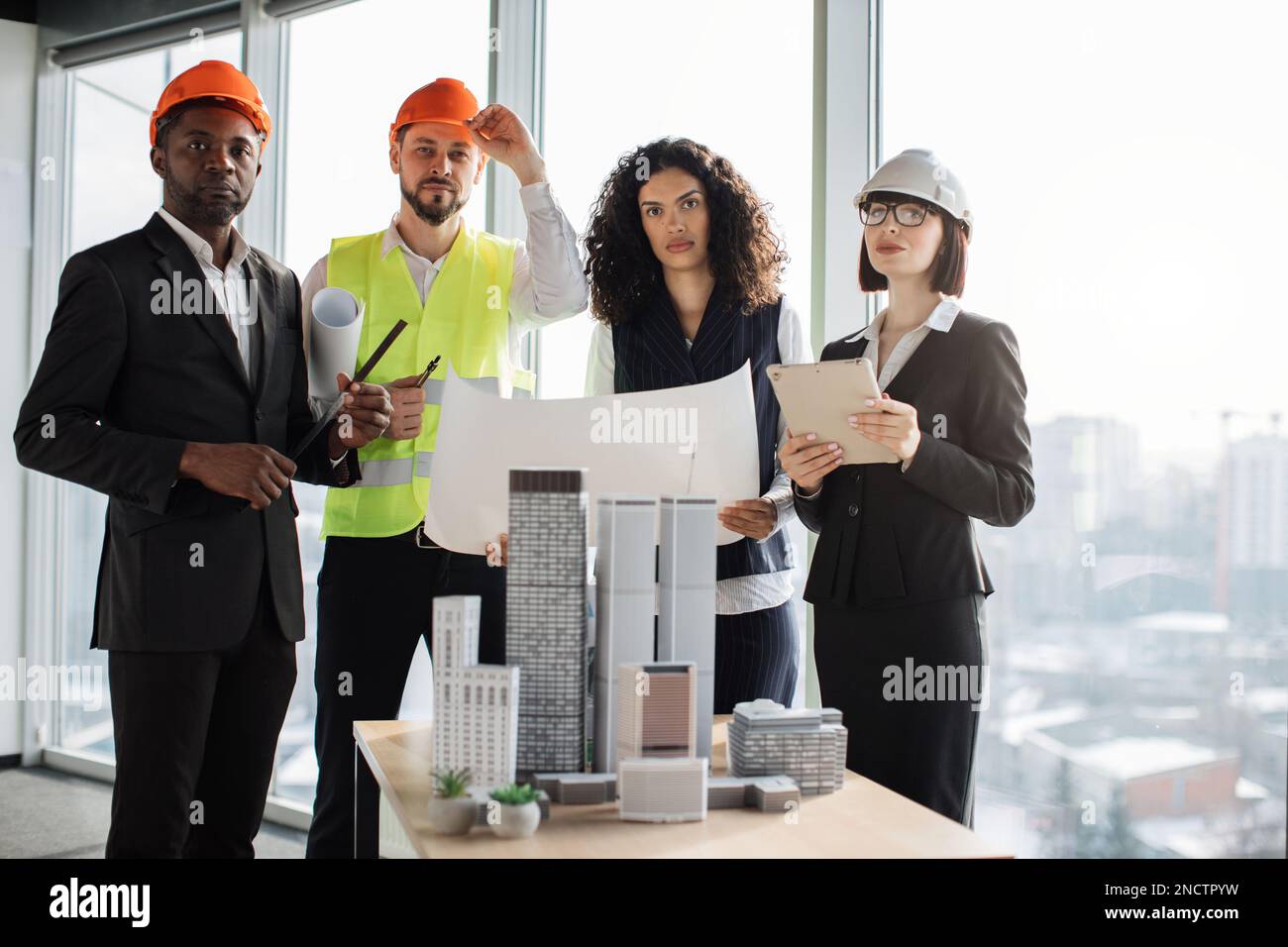 Group of four colleagues standing near building complex prototype ...