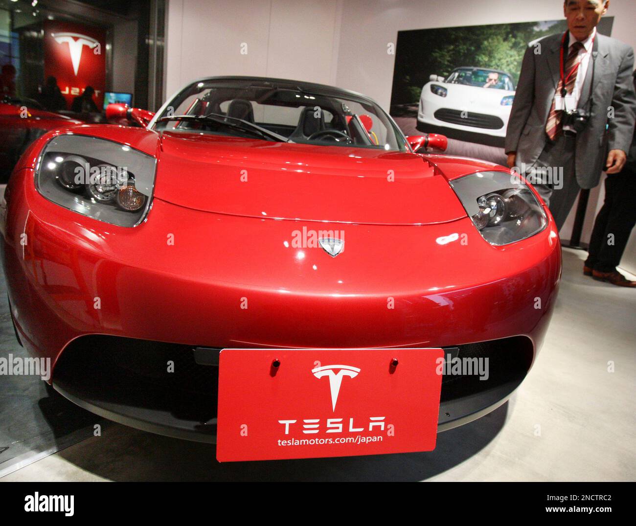 A guest walks by a Tesla electric sports car which is on display at ...