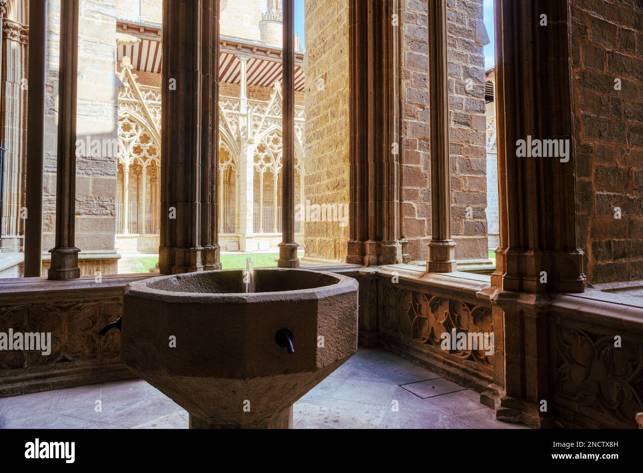 The Holy Water stoup in the ornate gothic cloister arcade arches of the ...