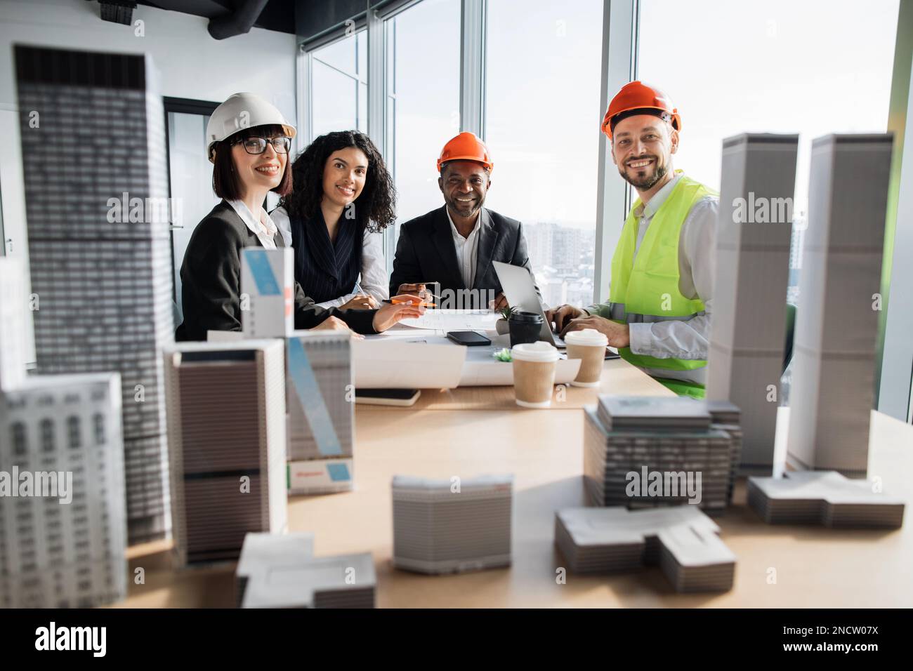 Multiracial coworkers builders and architects sitting at table with ...