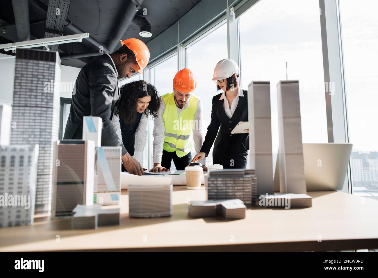 Group of four multiracial people architects standing near desk with ...