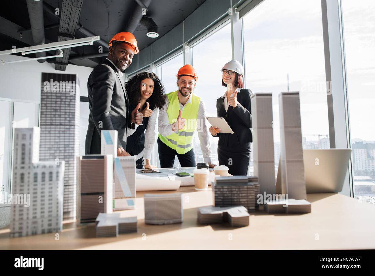 Multiracial coworkers builders and architects standing at table with ...