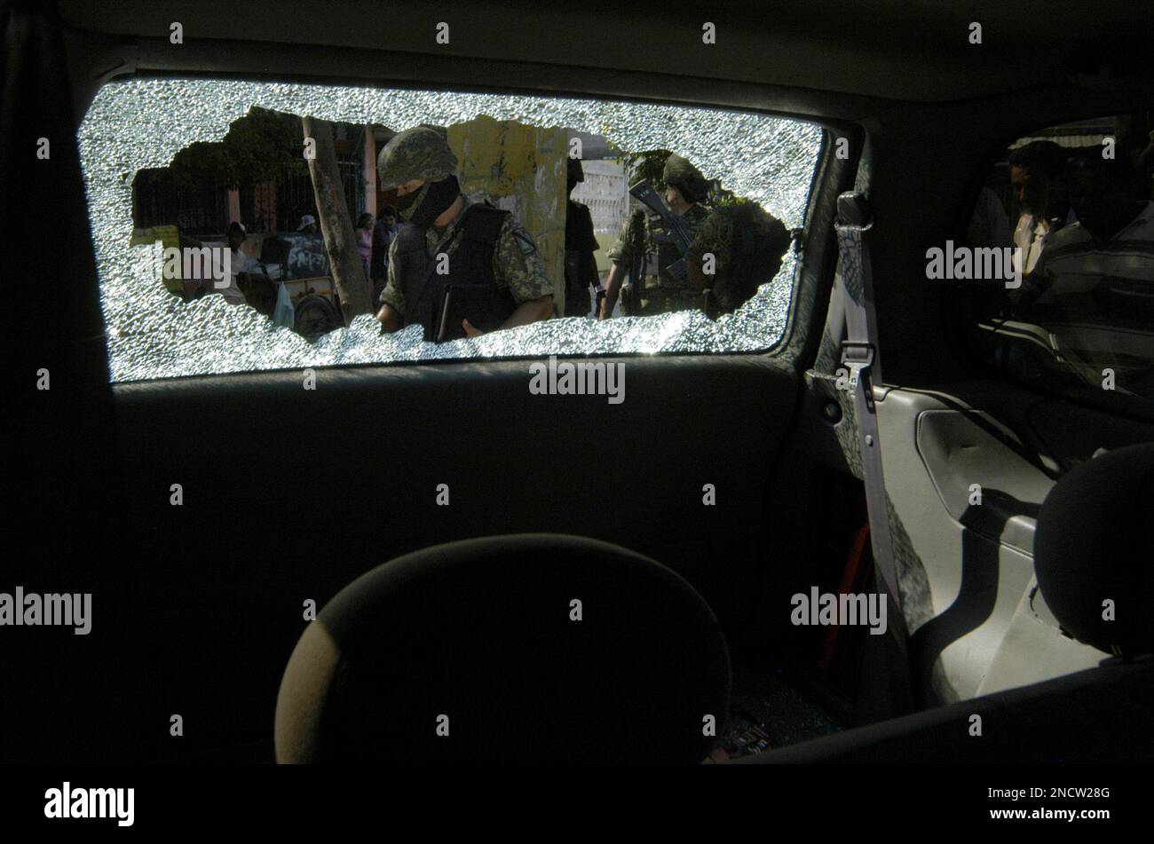 Soldiers seen through a smashed car window inspect a crime scene after ...