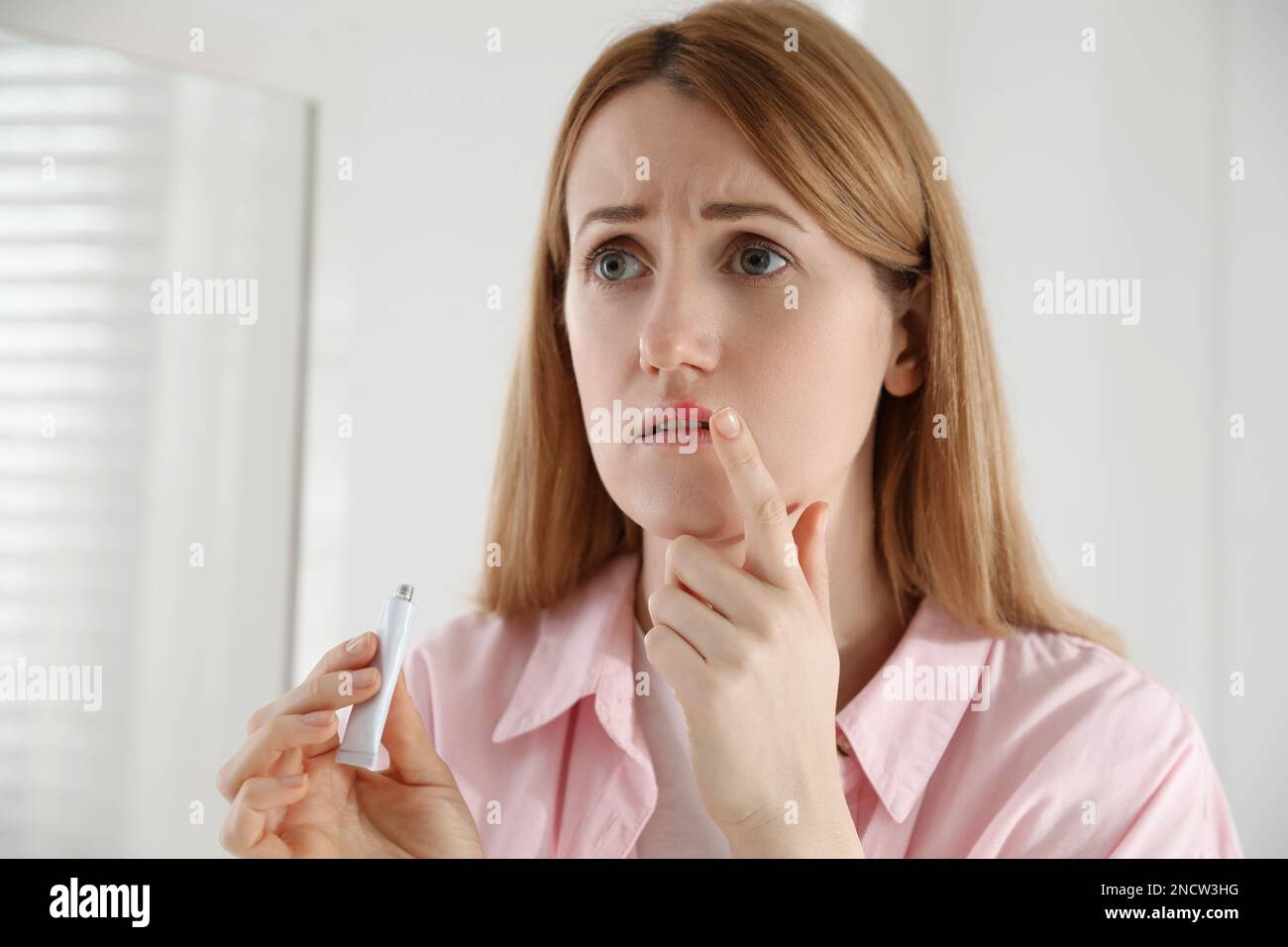 Upset woman with herpes applying cream on lips indoors Stock Photo - Alamy