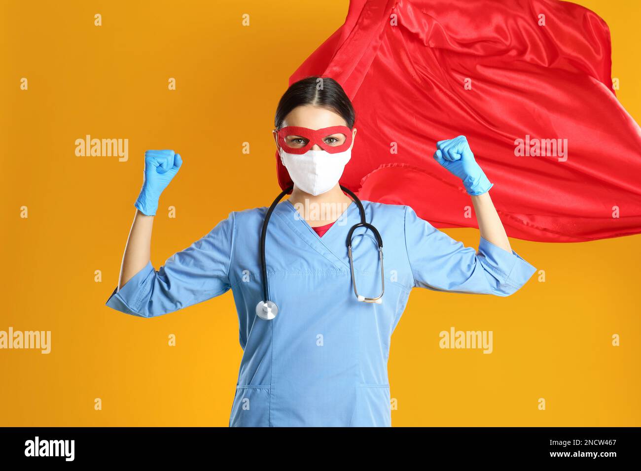 Doctor dressed as superhero posing on yellow background. Concept of ...