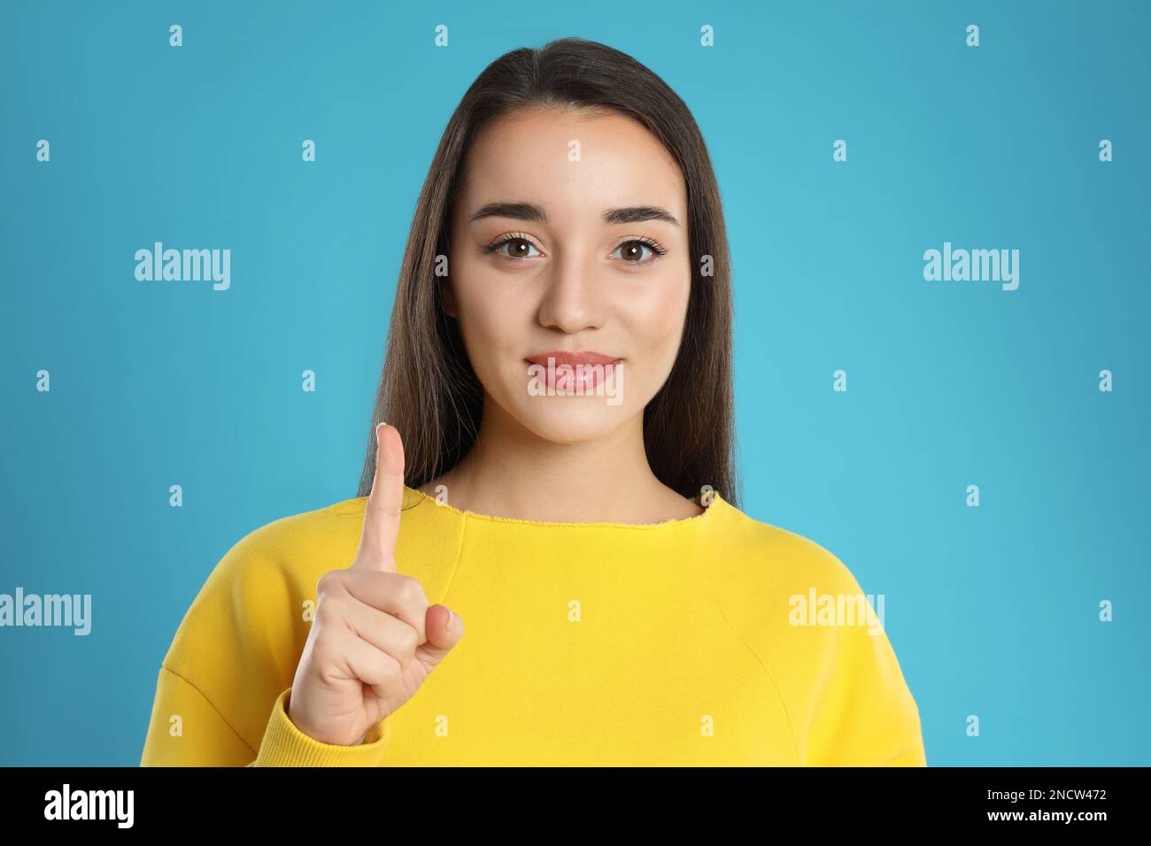 Woman showing number one with her hand on light blue background Stock ...