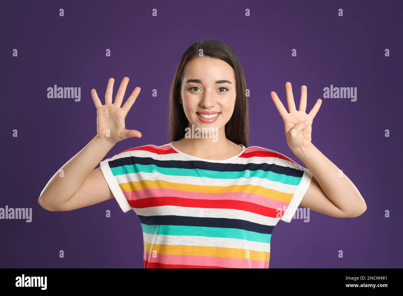Woman showing number nine with her hands on purple background Stock ...