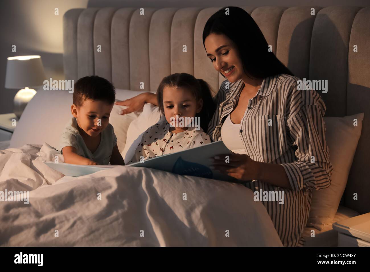 Mother reading bedtime story to her children at home Stock Photo - Alamy