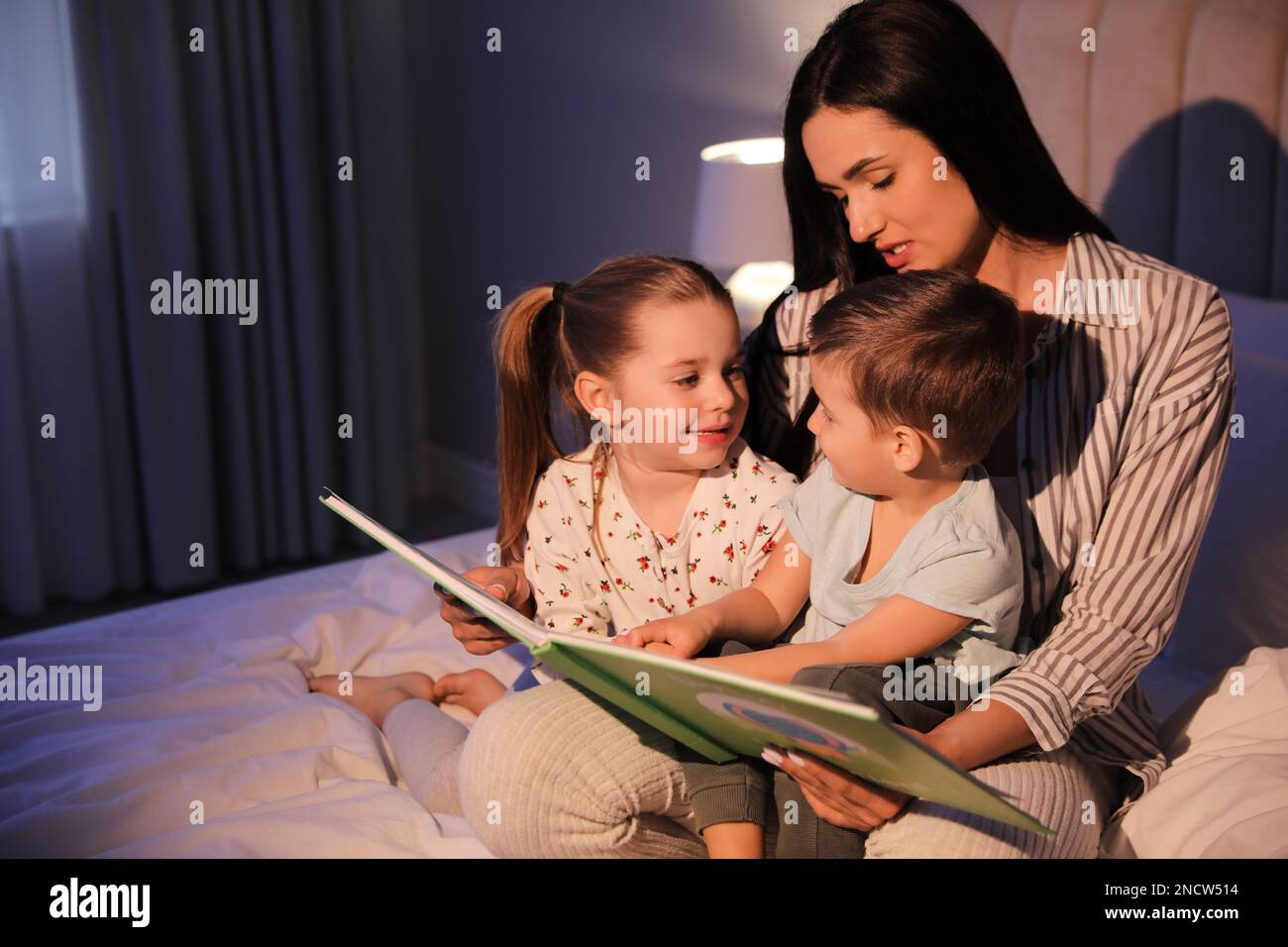 Mother reading bedtime story to her children at home Stock Photo - Alamy