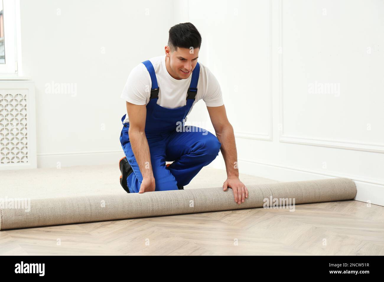 Worker rolling out new carpet in room Stock Photo - Alamy Worker rolling out new carpet in room Stock Photo - Alamy