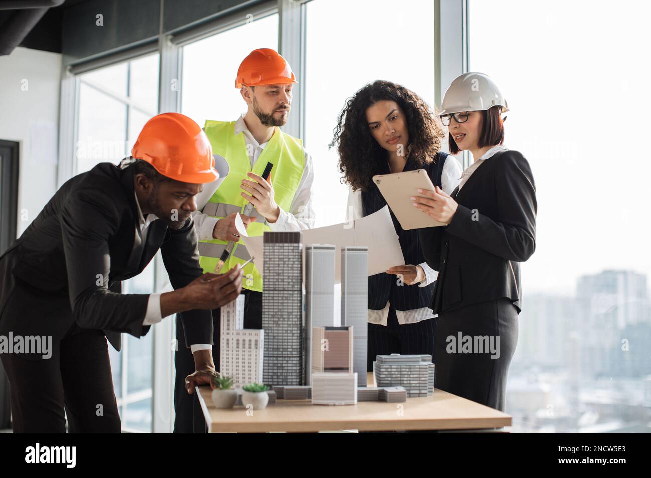 Group of four multiracial people architects standing near desk with ...