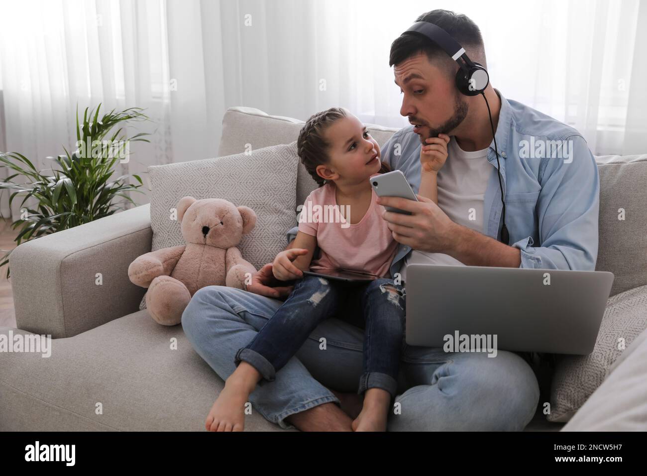 Multitasking man combining parenting and work at home Stock Photo - Alamy