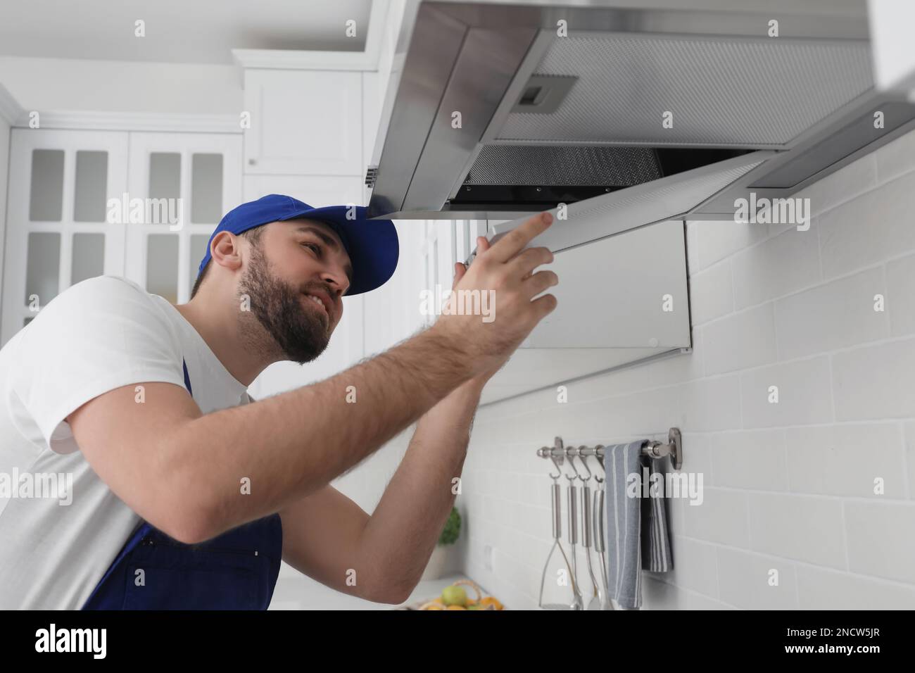 Worker repairing modern cooker hood in kitchen Stock Photo - Alamy