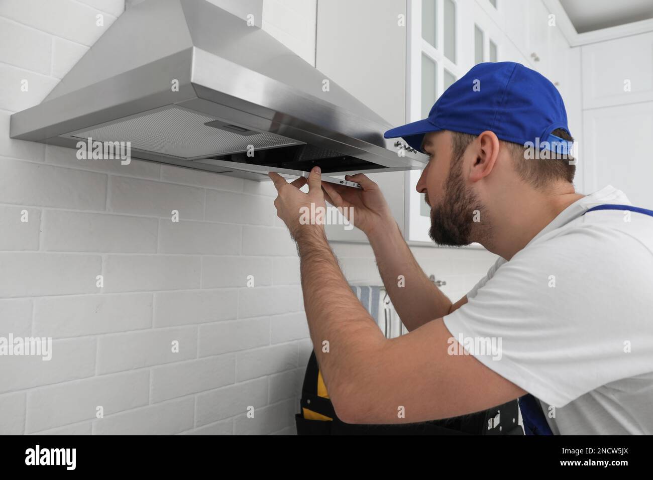 Worker repairing modern cooker hood in kitchen Stock Photo - Alamy