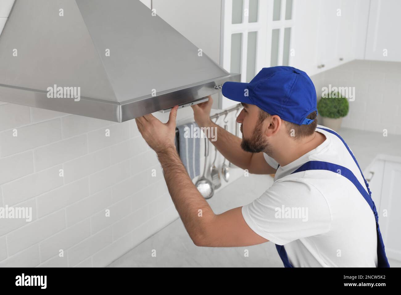 Worker repairing modern cooker hood in kitchen Stock Photo - Alamy