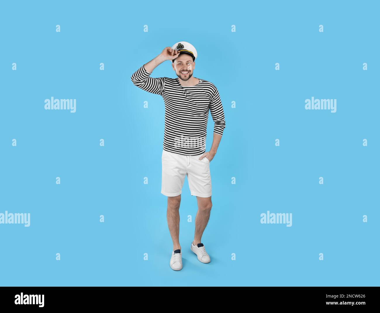 Happy sailor wearing cap on light blue background Stock Photo - Alamy