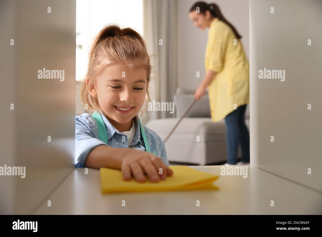 Little girl helping her mother with cleaning living room Stock Photo ...