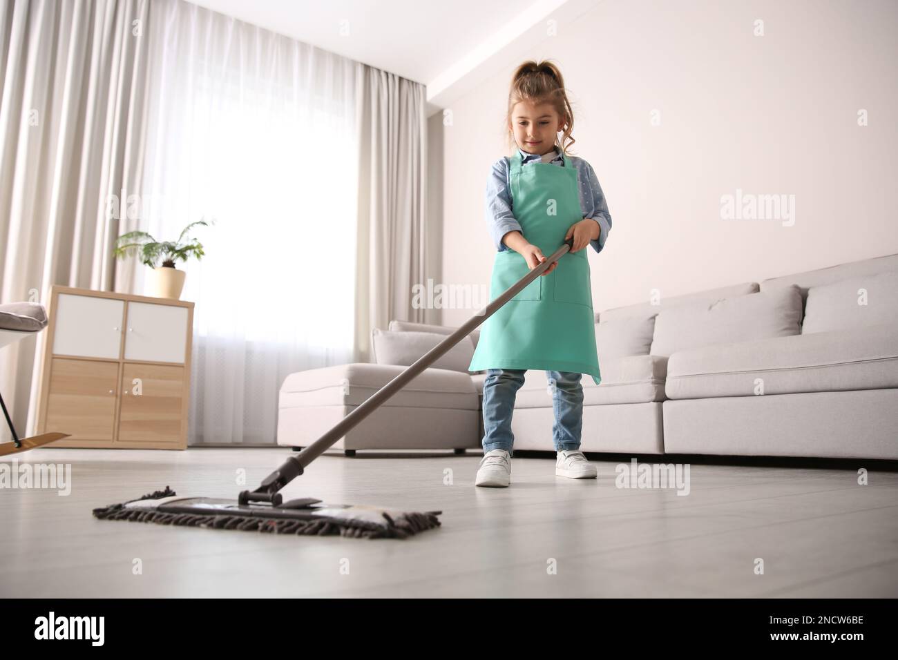 Little girl mopping floor in living room at home Stock Photo - Alamy