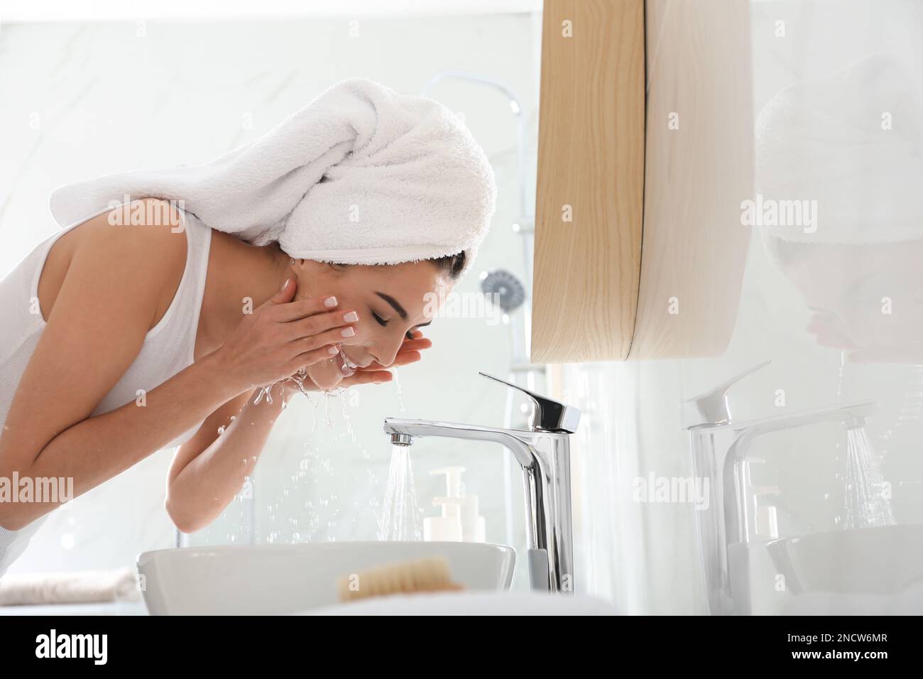 Happy young woman washing face in bathroom Stock Photo - Alamy