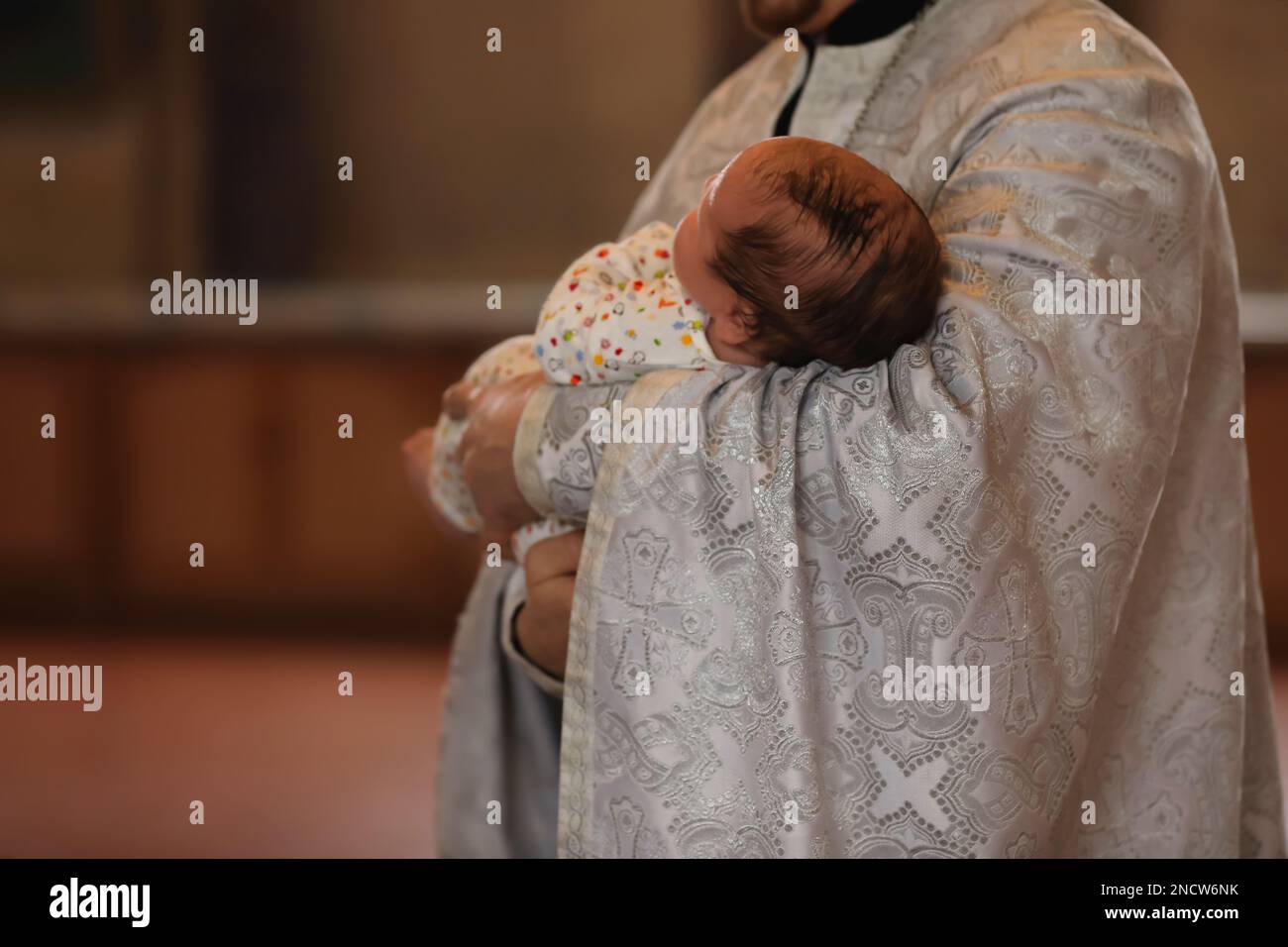 Priest holding adorable baby in church during baptism ceremony, closeup ...