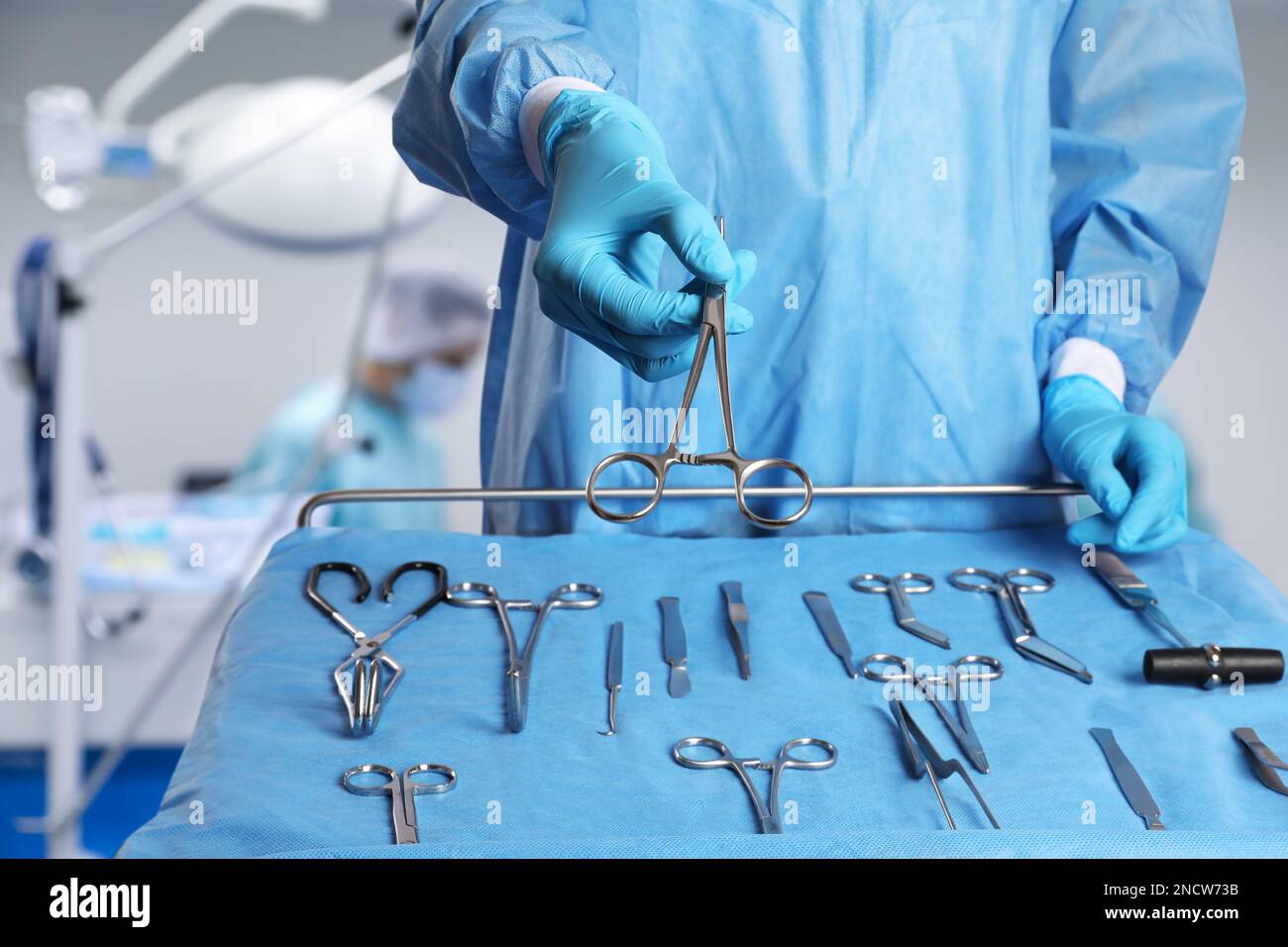 Nurse near table with different surgical instruments in operating room ...