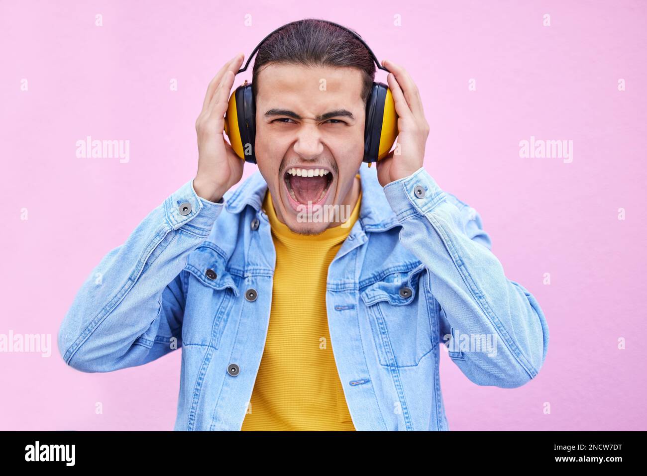 Headphones, man and screaming portrait on background, pink wall ...